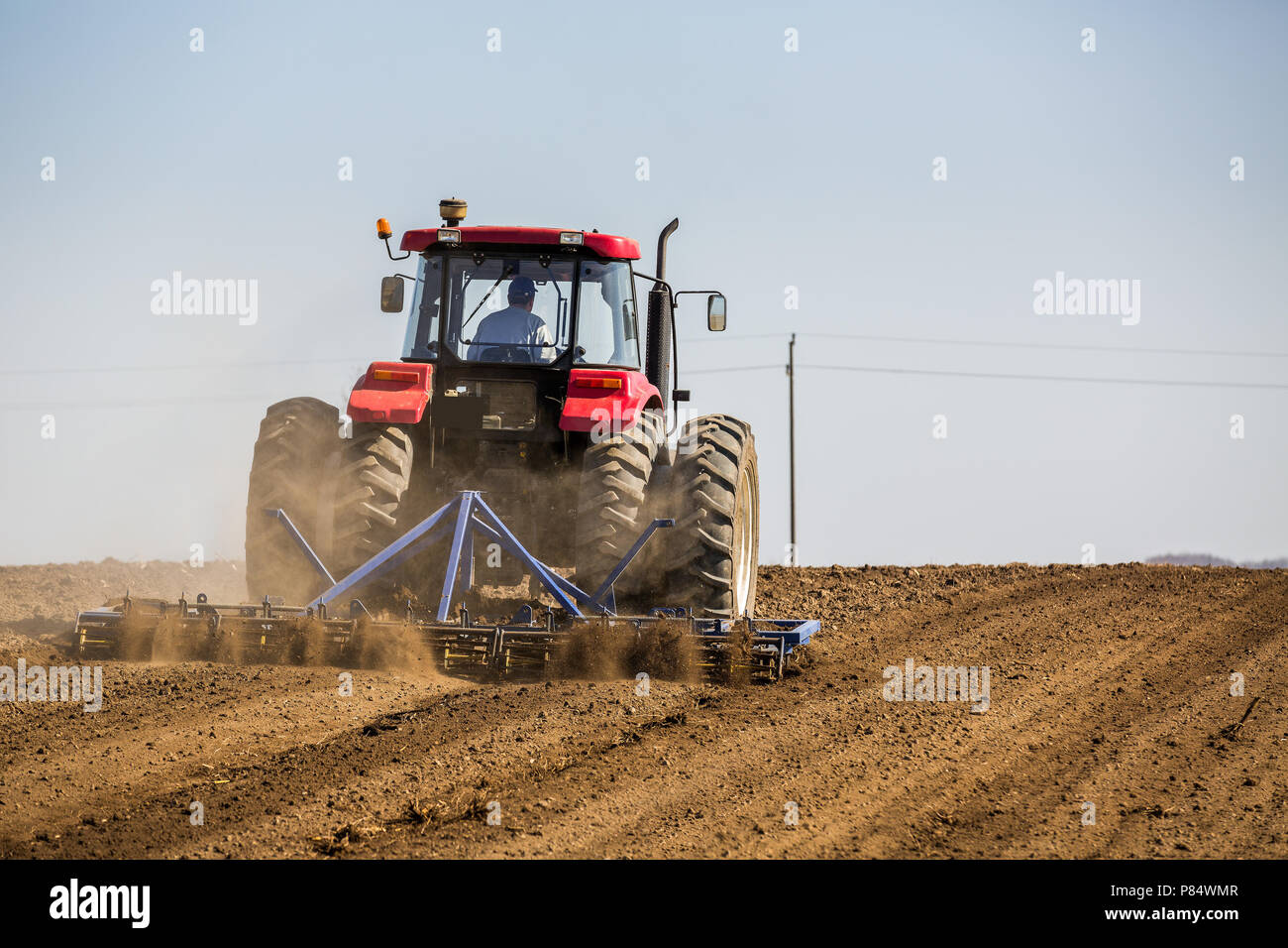 Tractor cultivating field at spring Stock Photo - Alamy