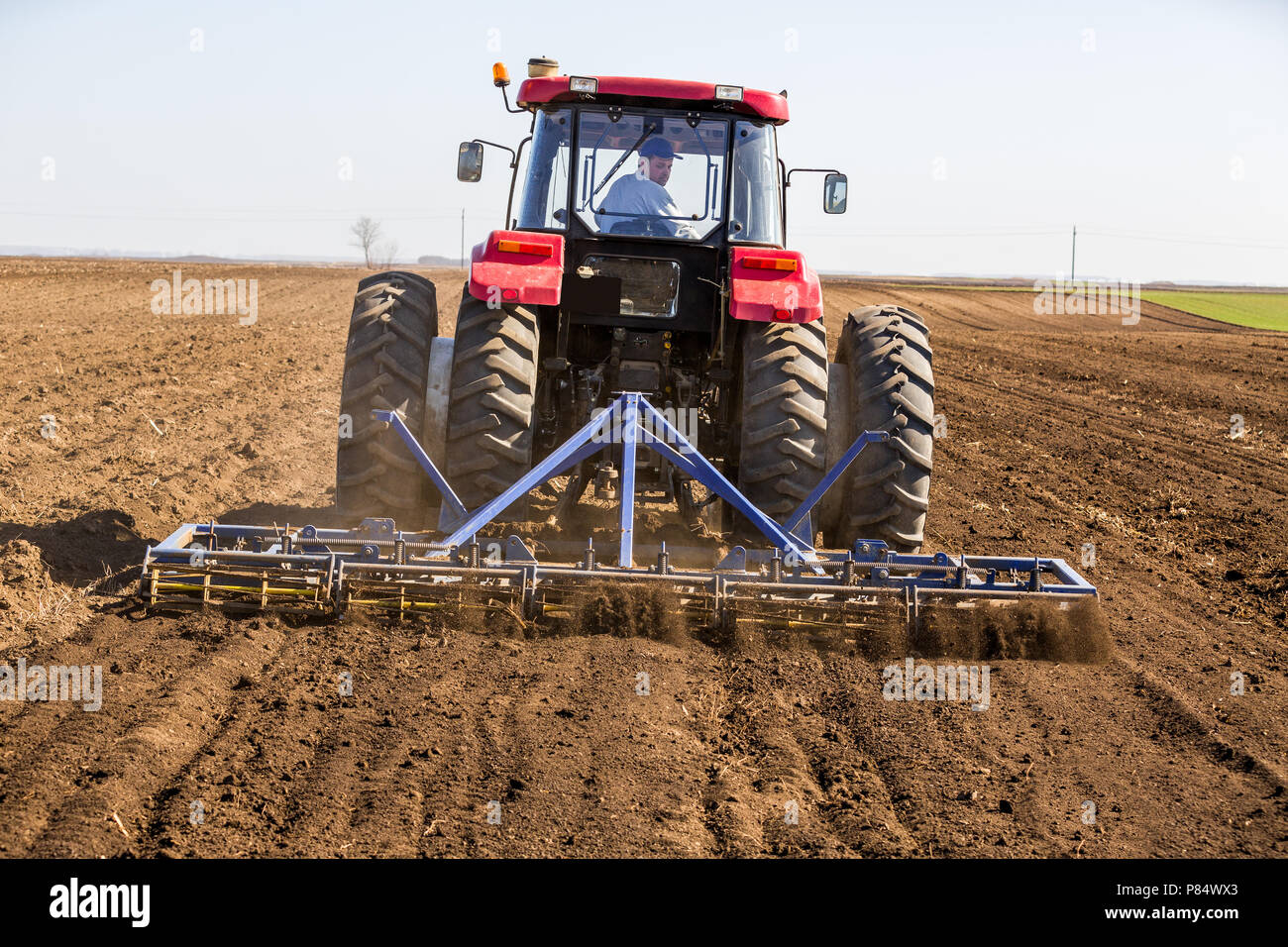 Tractor cultivating field at spring Stock Photo - Alamy