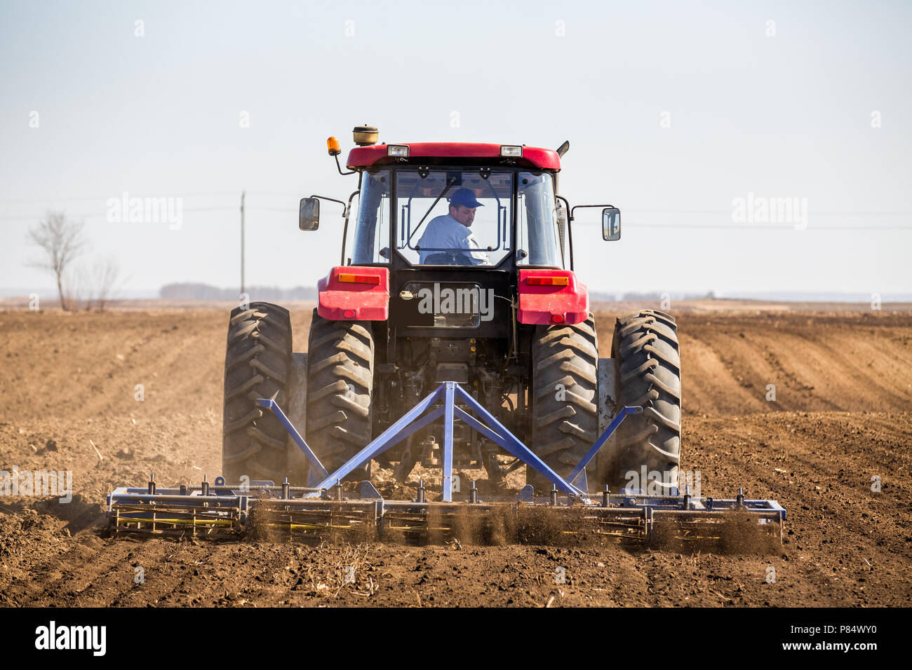 Tractor cultivating field at spring Stock Photo - Alamy