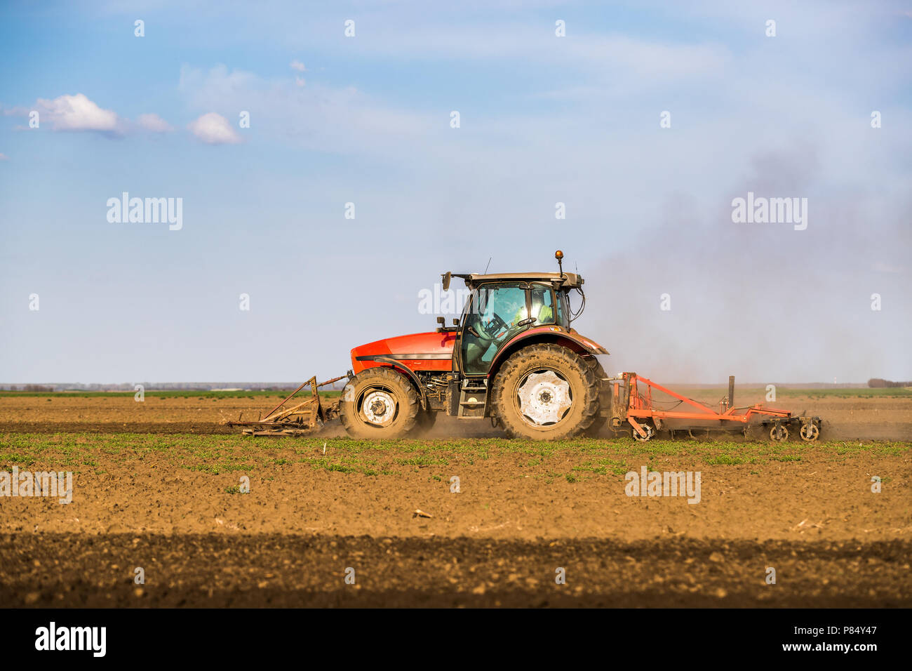 Tractor cultivating field at spring Stock Photo - Alamy
