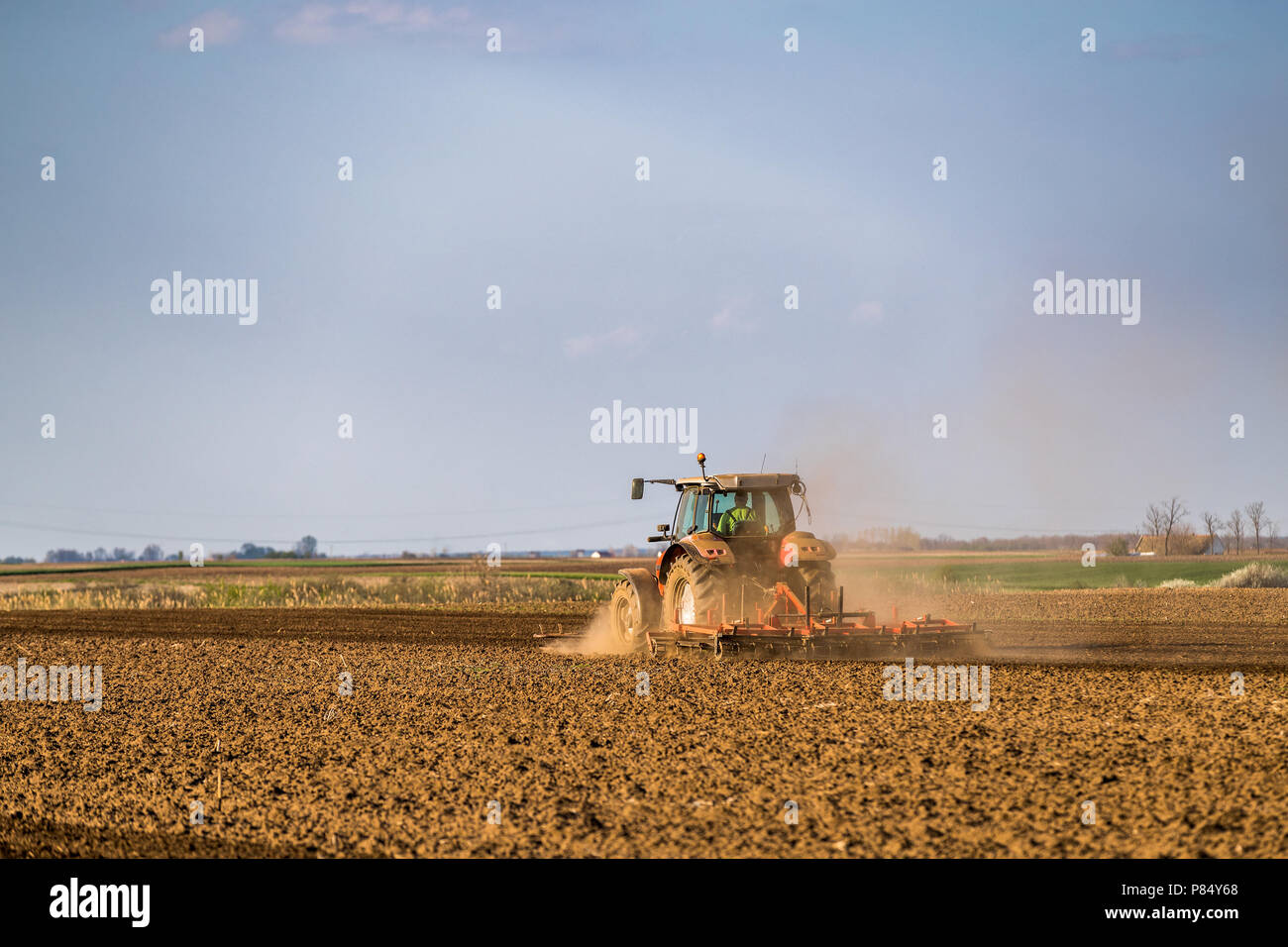 Tractor cultivating field at spring Stock Photo - Alamy