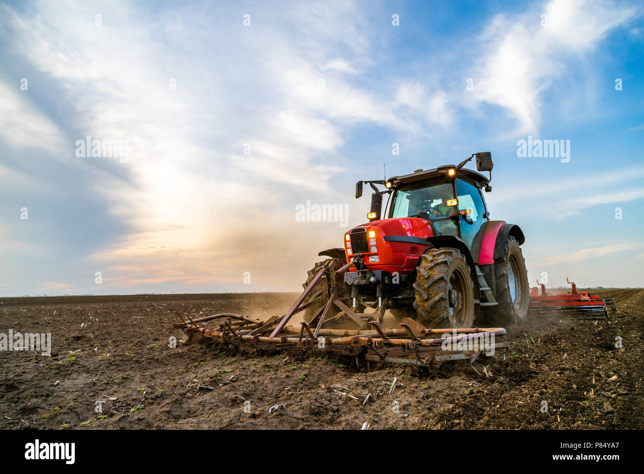 Tractor cultivating field at spring Stock Photo - Alamy