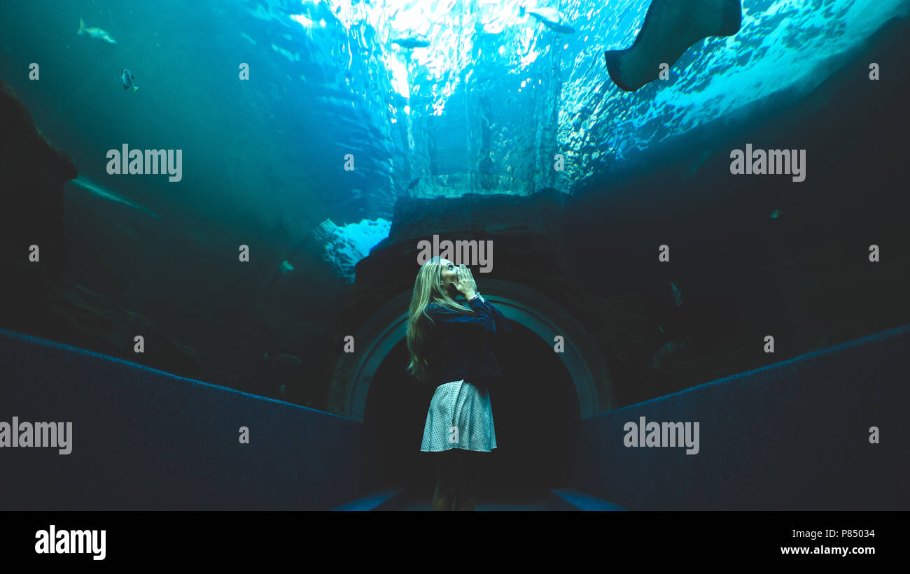 Woman standing in a walkway underwater in a aquarium. Tourist visiting ...