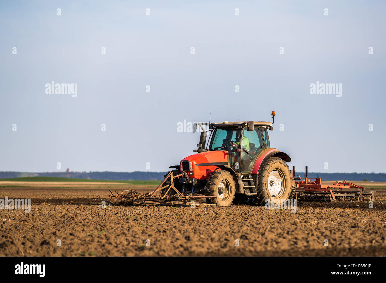Tractor cultivating field at spring Stock Photo - Alamy