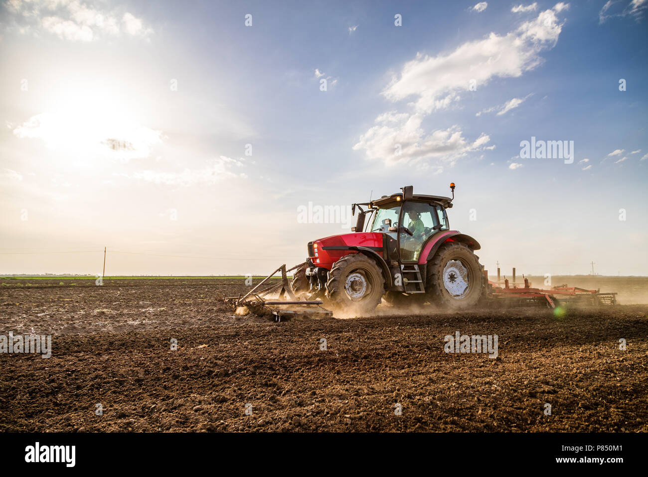 Tractor cultivating field at spring Stock Photo - Alamy
