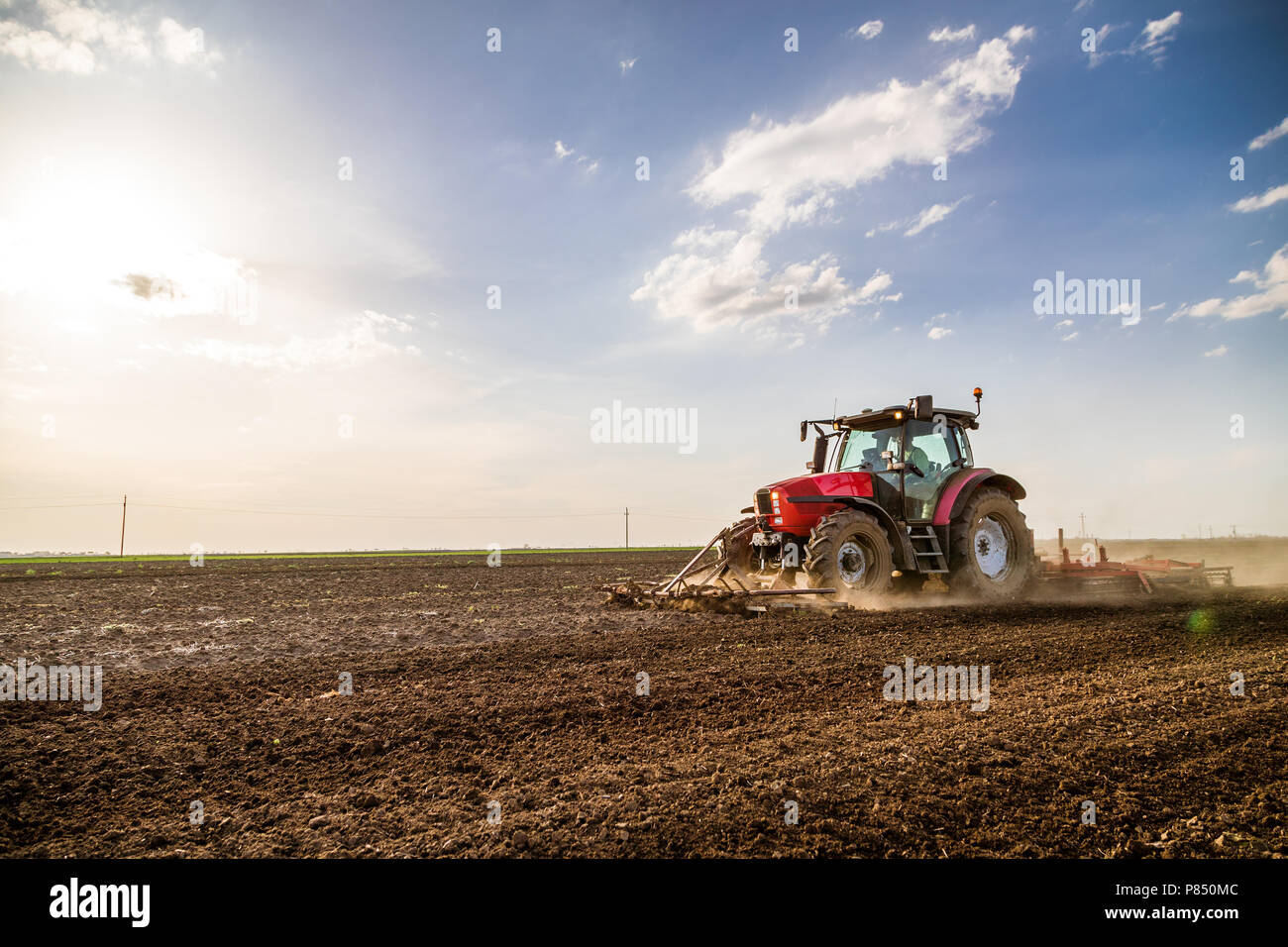 Tractor cultivating field at spring Stock Photo - Alamy