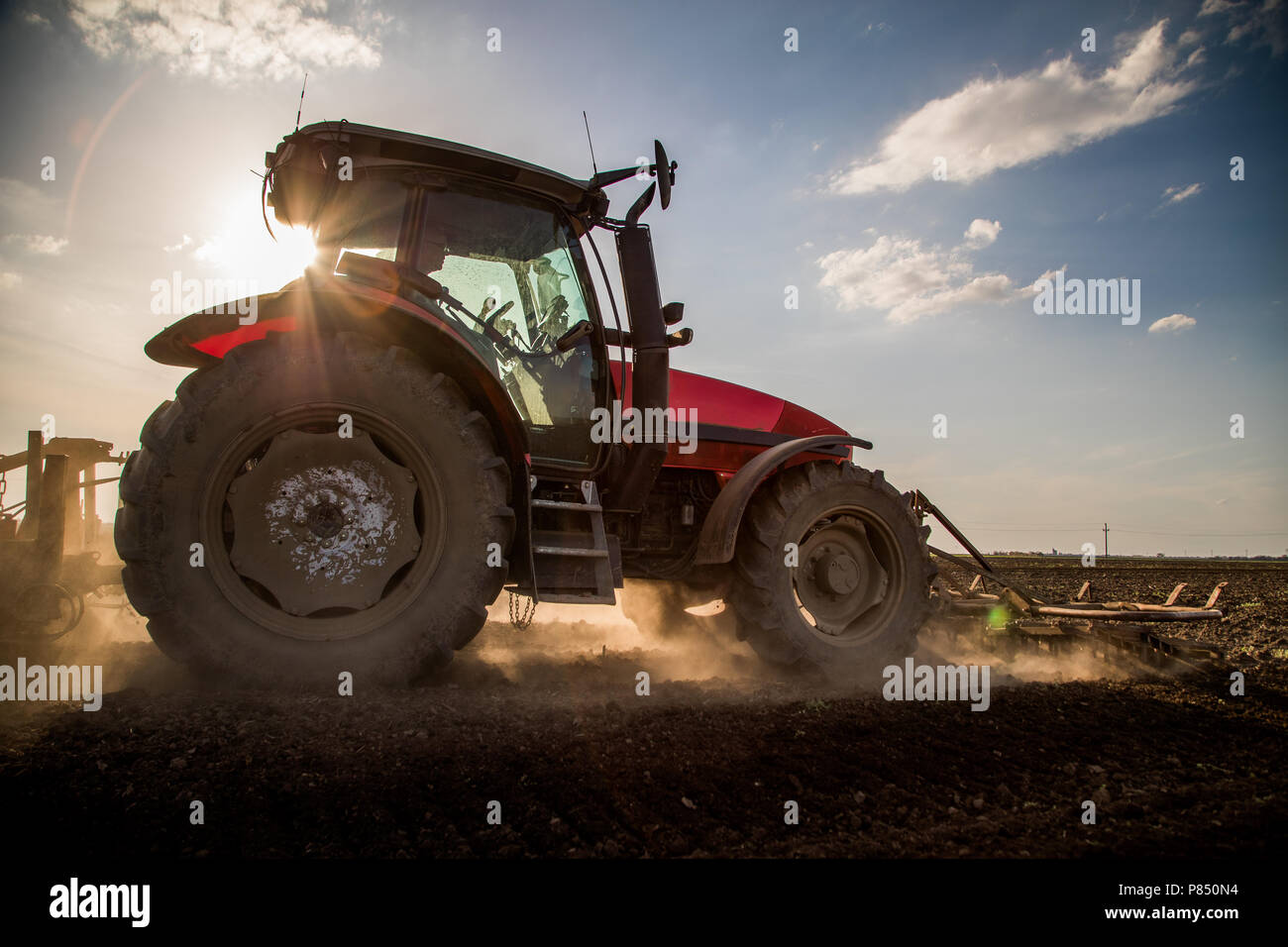 Tractor cultivating field at spring Stock Photo - Alamy