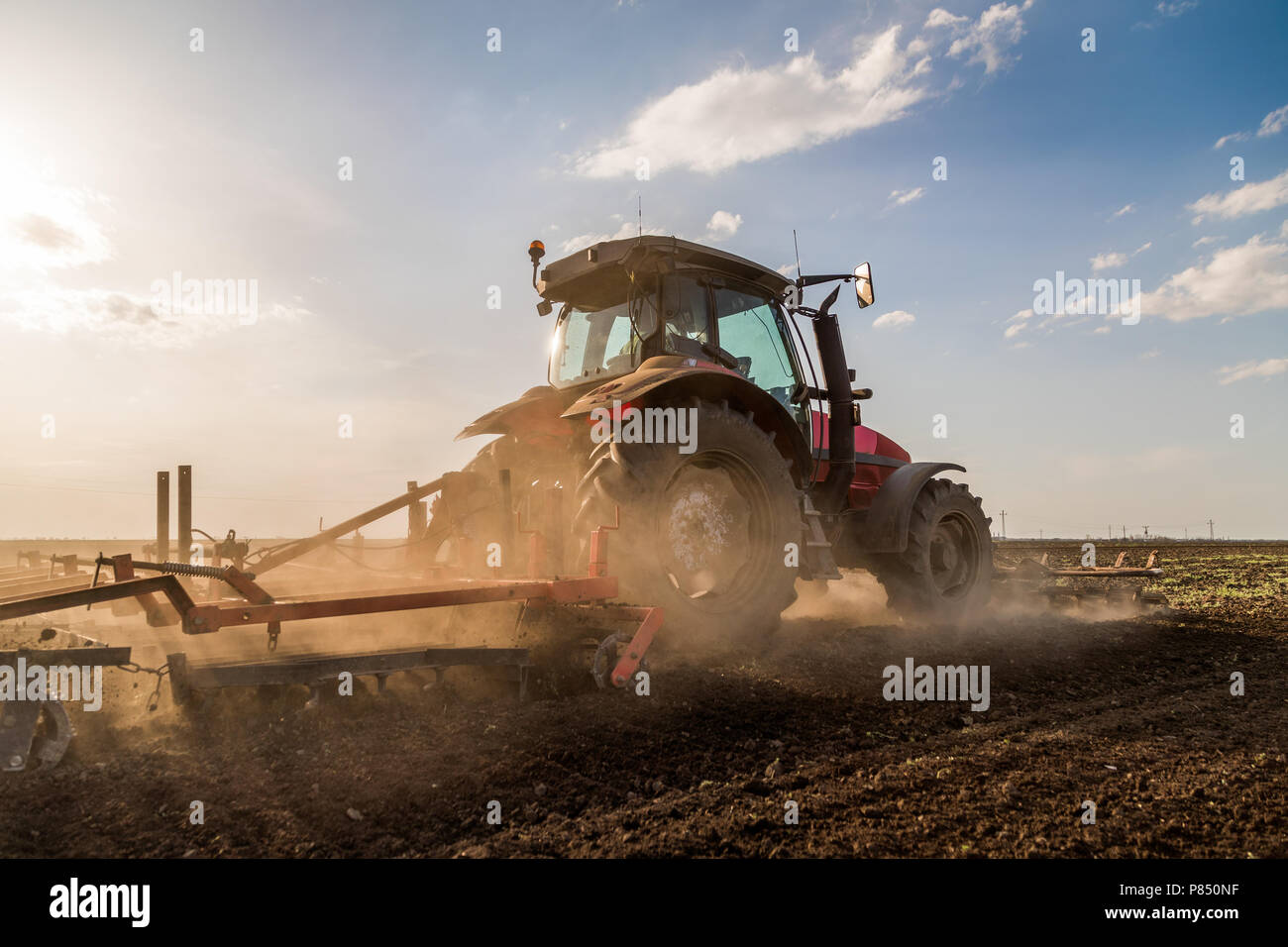 Tractor cultivating field at spring Stock Photo - Alamy