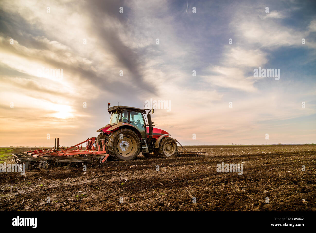 Tractor cultivating field at spring Stock Photo - Alamy