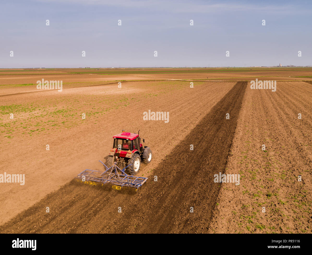 Aerial shot of a tractor cultivating field at spring Stock Photo - Alamy