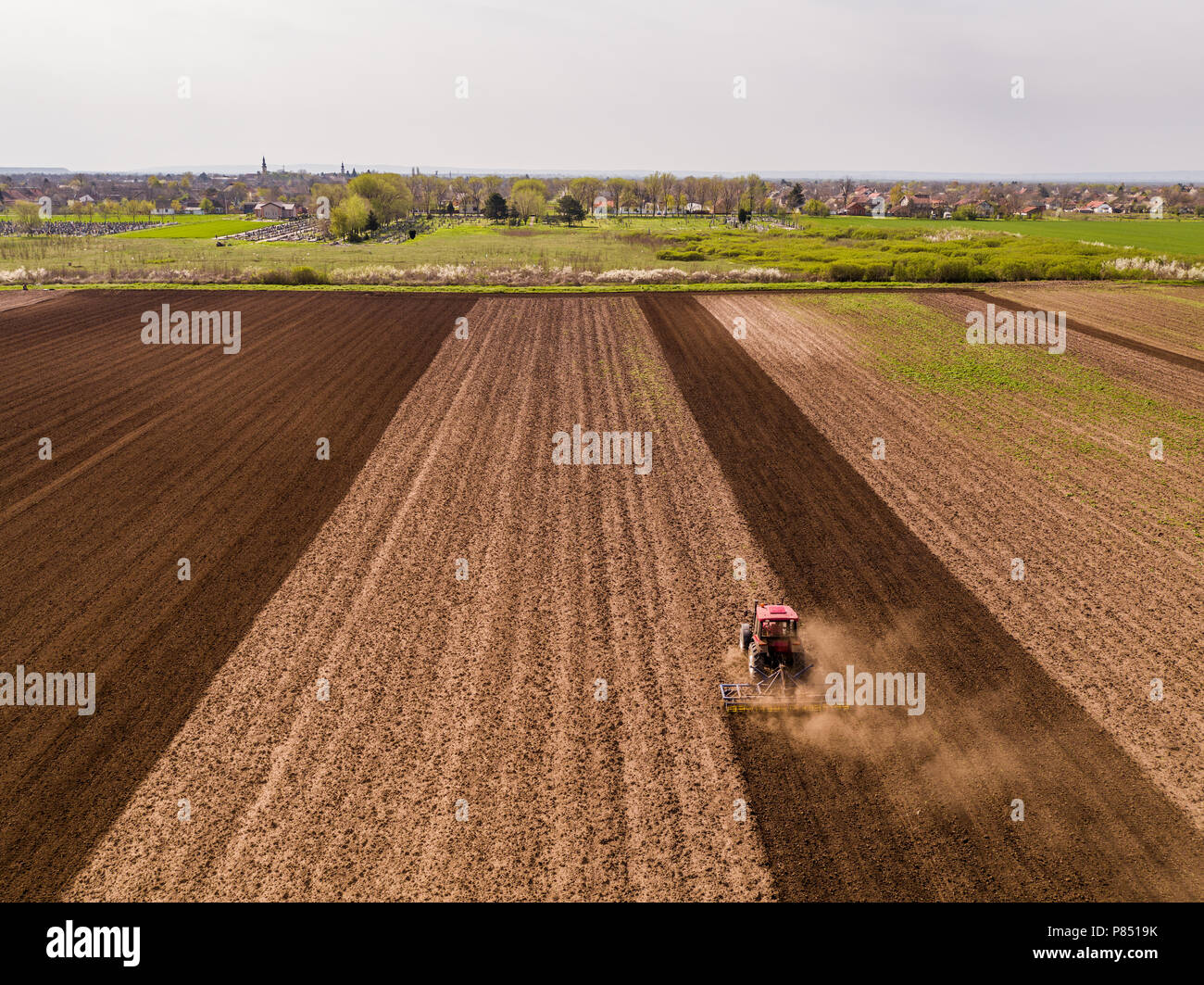 Aerial shot of a tractor cultivating field at spring Stock Photo - Alamy