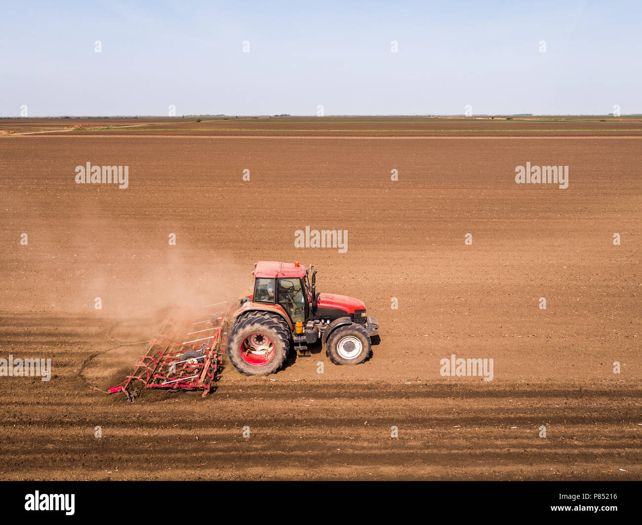 Aerial shot of a tractor cultivating field at spring Stock Photo - Alamy