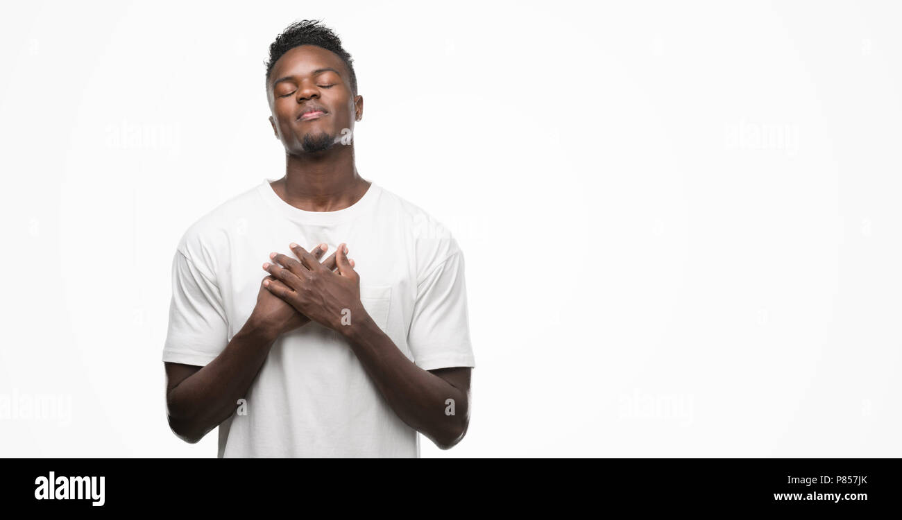 Young african american man wearing white t-shirt smiling with hands on ...