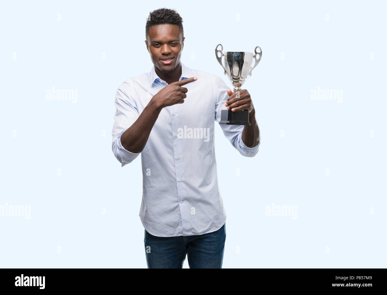 Young african american man holding trophy very happy pointing with hand ...