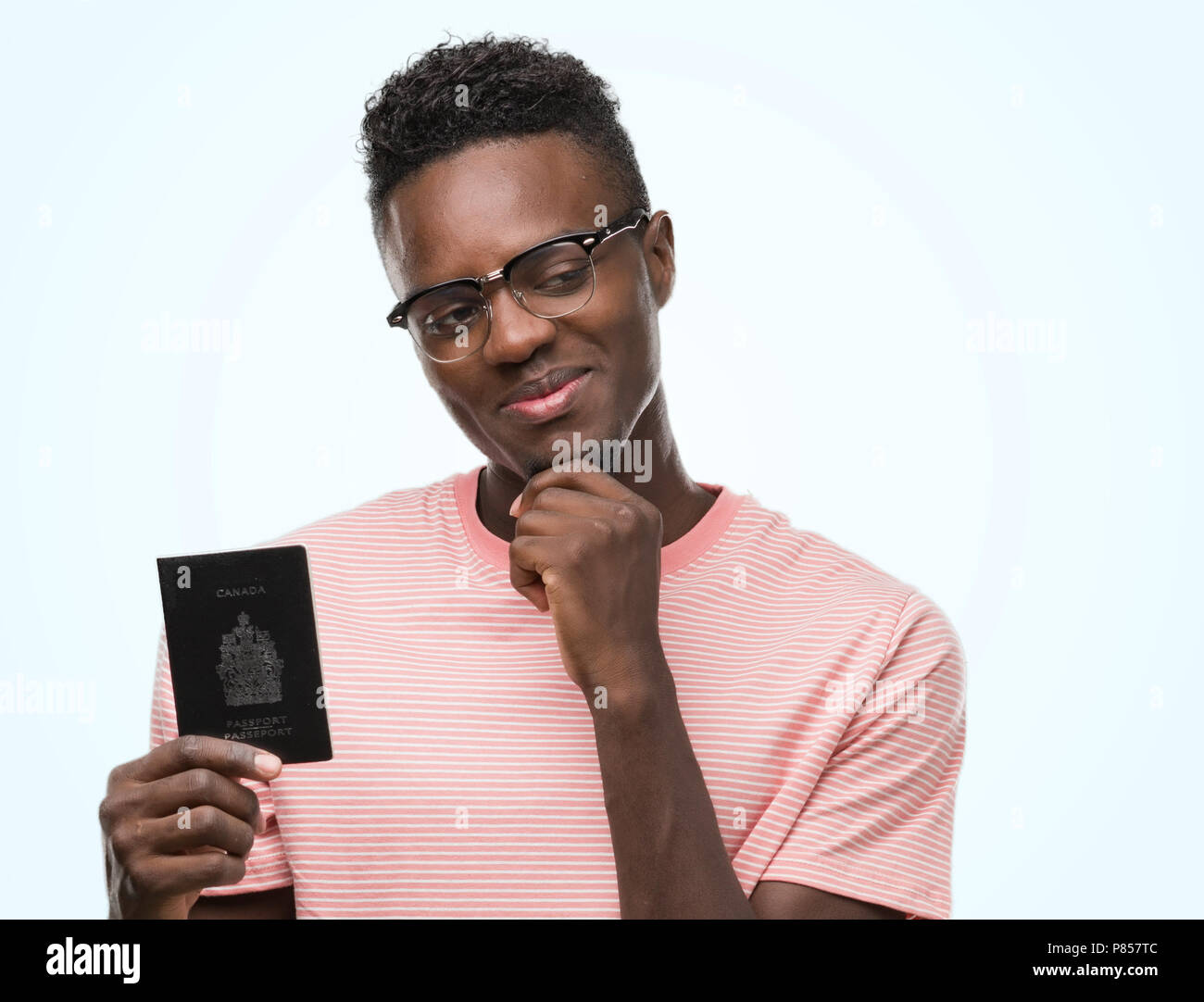 Young african american man holding canadian passport serious face ...
