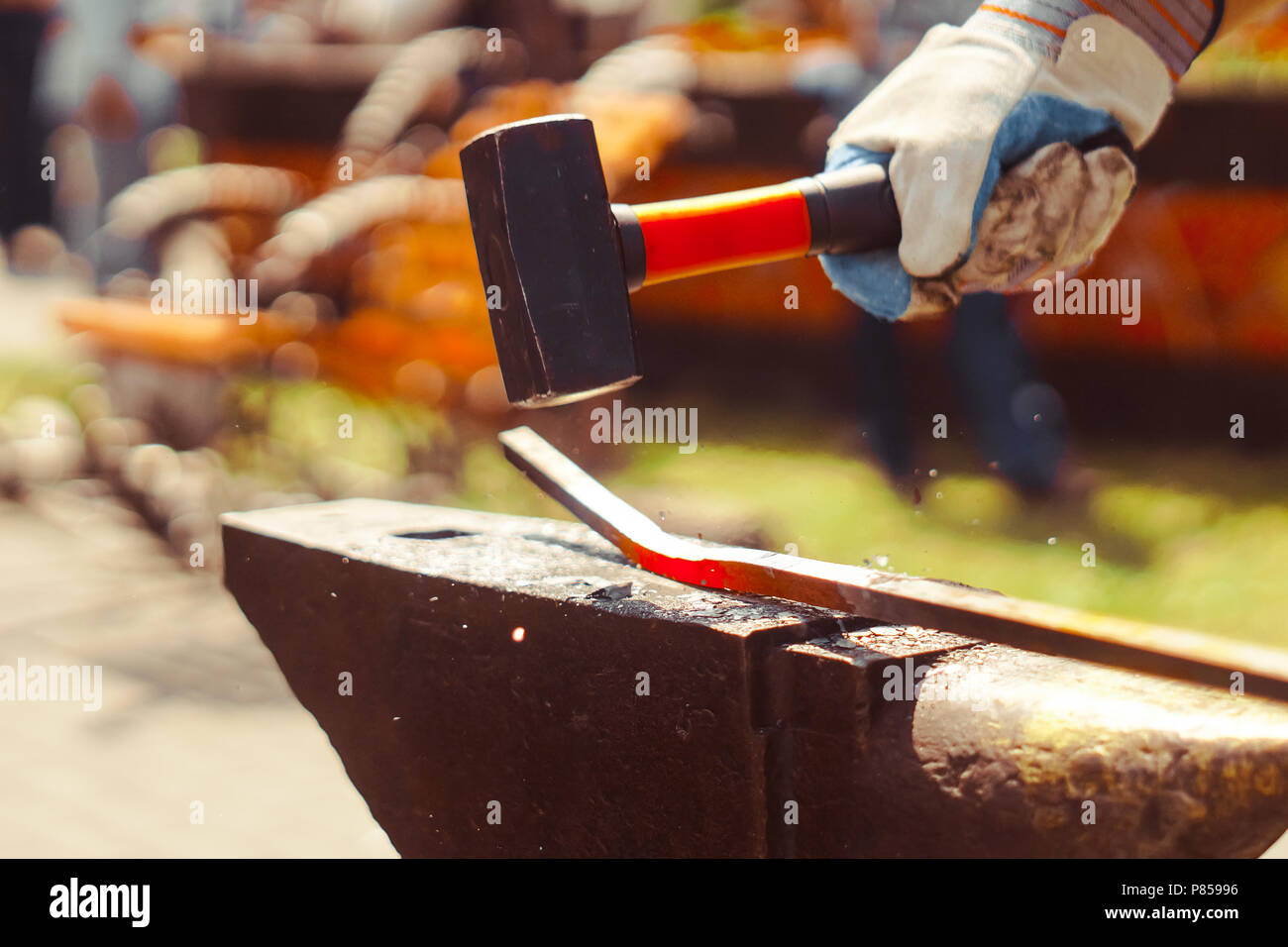 A blacksmith hammering a hot metal rod to shape it Stock Photo - Alamy