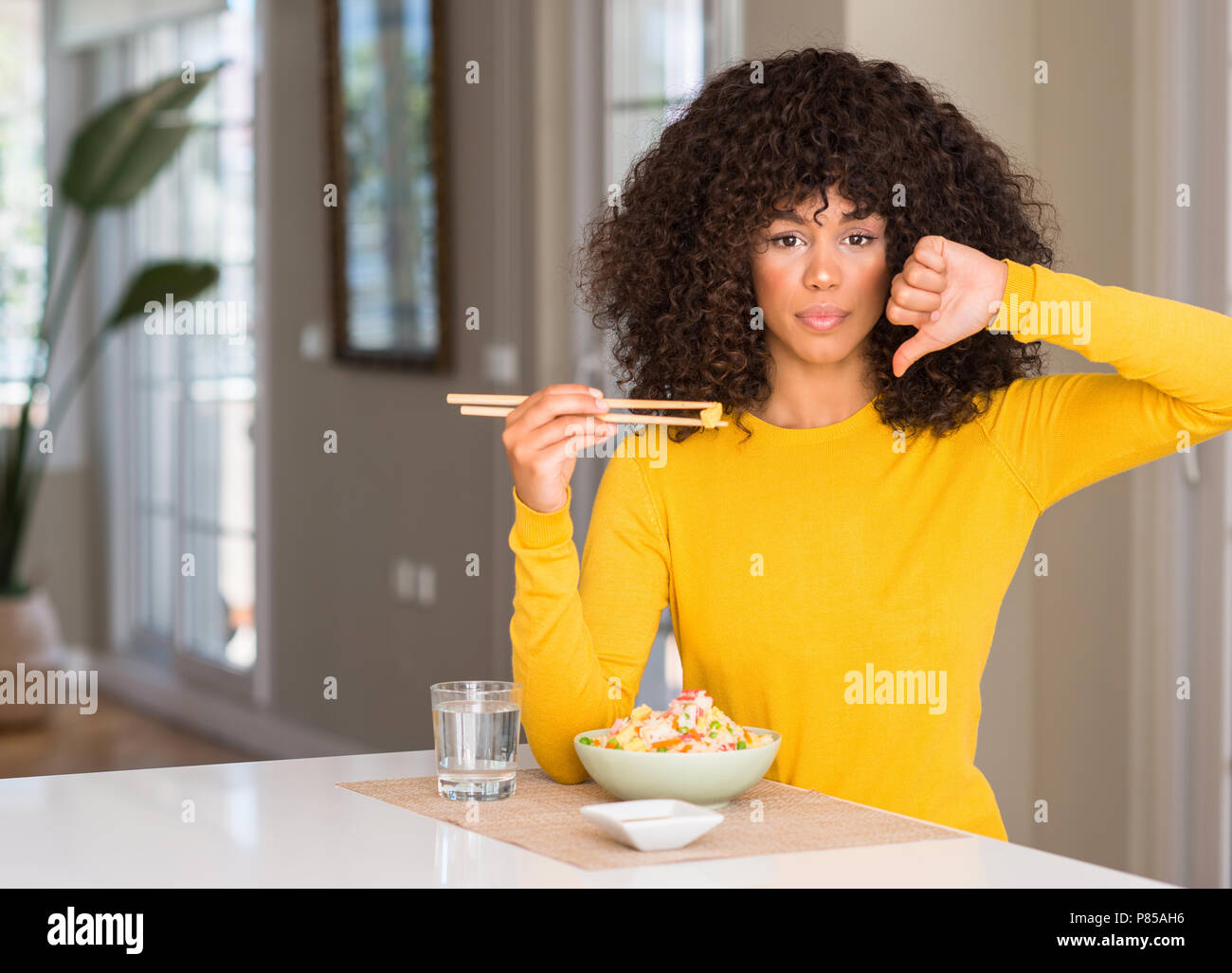 African american woman eating asian rice at home with angry face ...