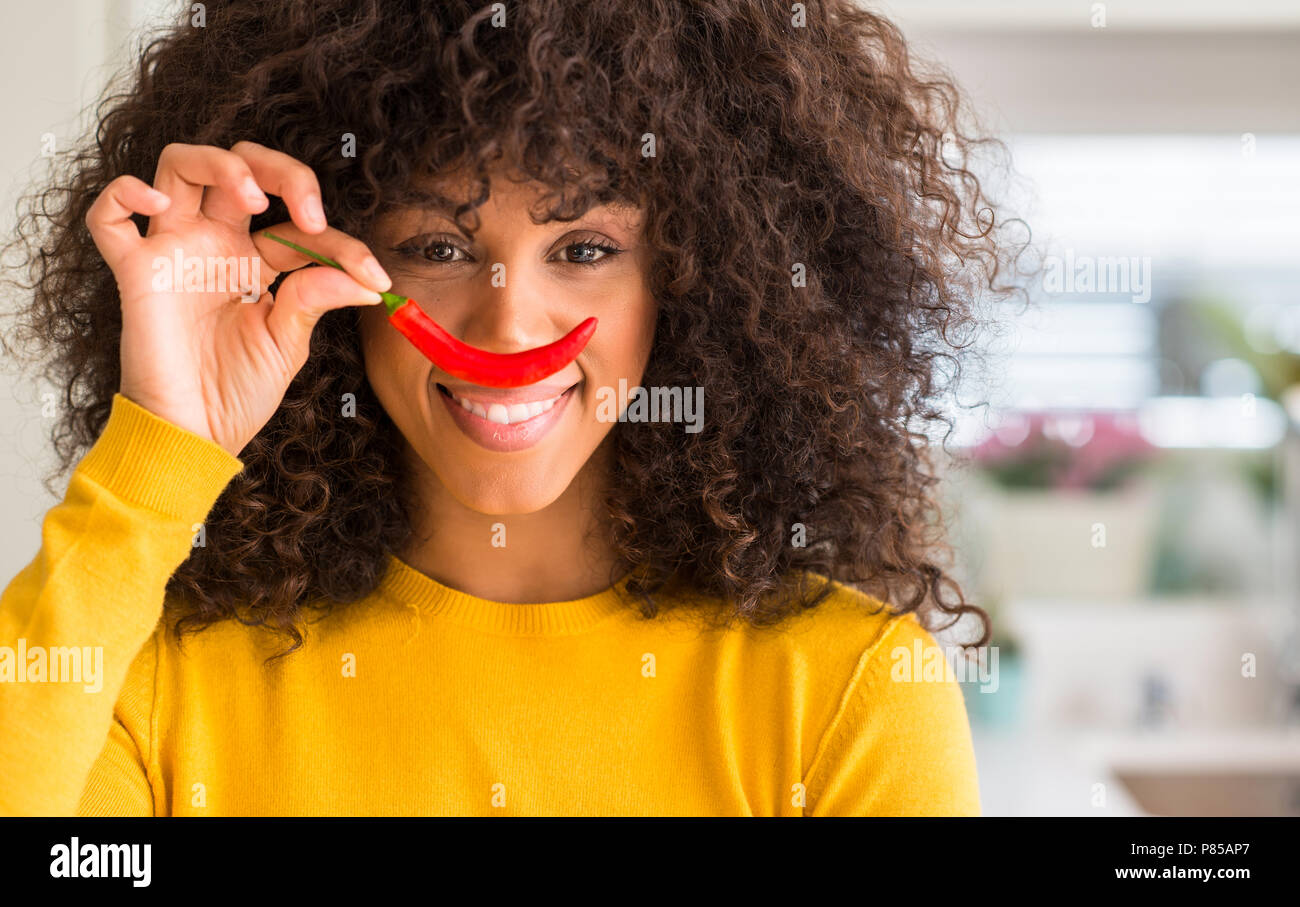 African american woman eating red hot chili pepper with a happy face ... African american woman eating red hot chili pepper with a happy face ...