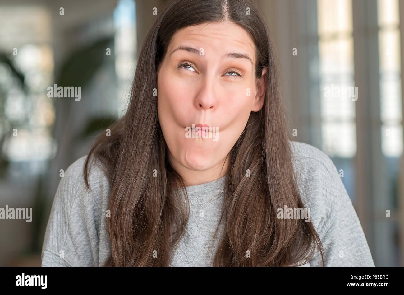Young beautiful woman at home making fish face with lips, crazy and ...