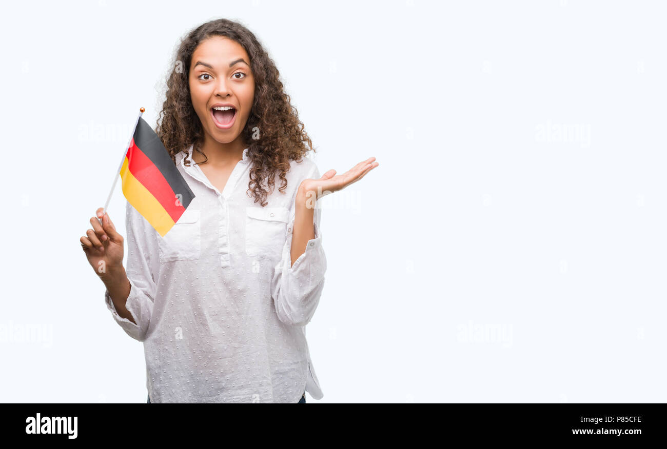 Young hispanic woman holding flag of Germany very happy and excited ...