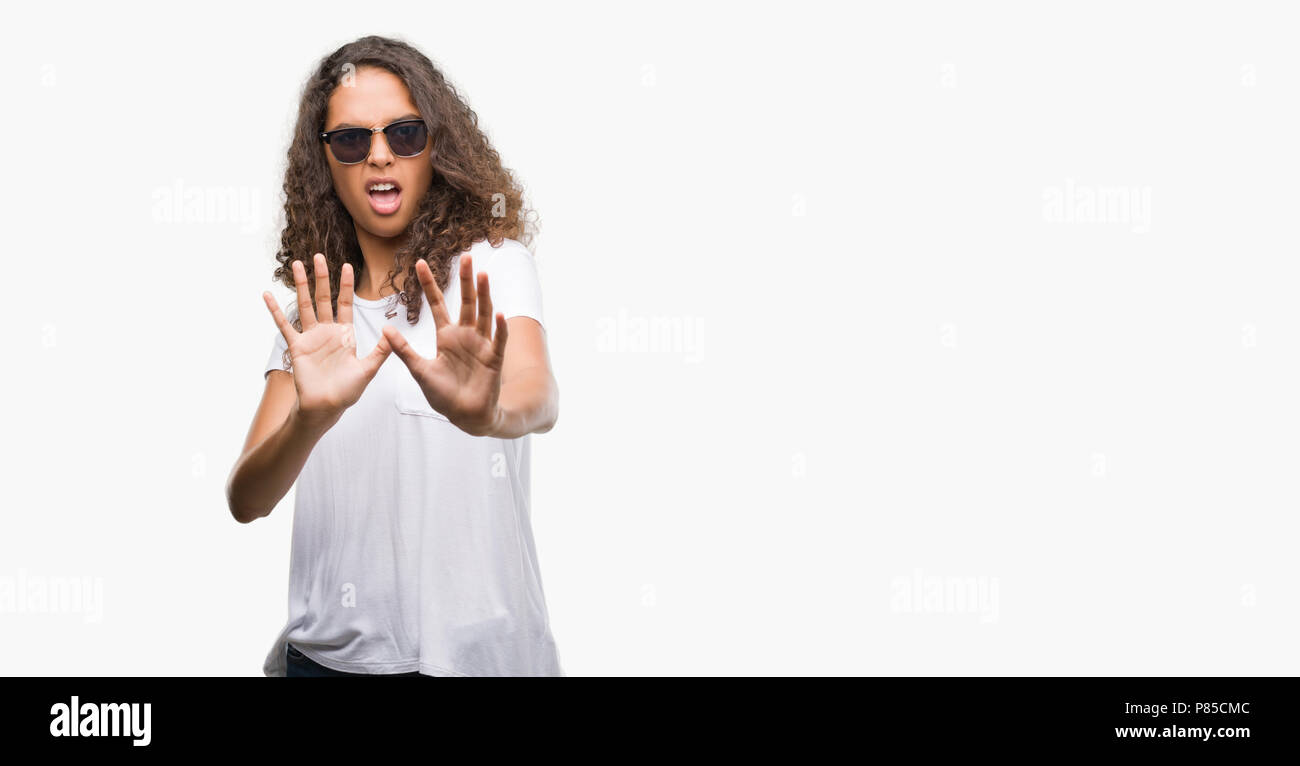 Young hispanic woman wearing sunglasses afraid and terrified with fear ...