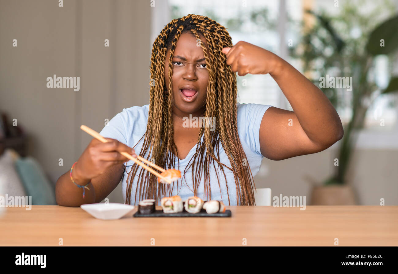 African american woman eating sushi annoyed and frustrated shouting ...