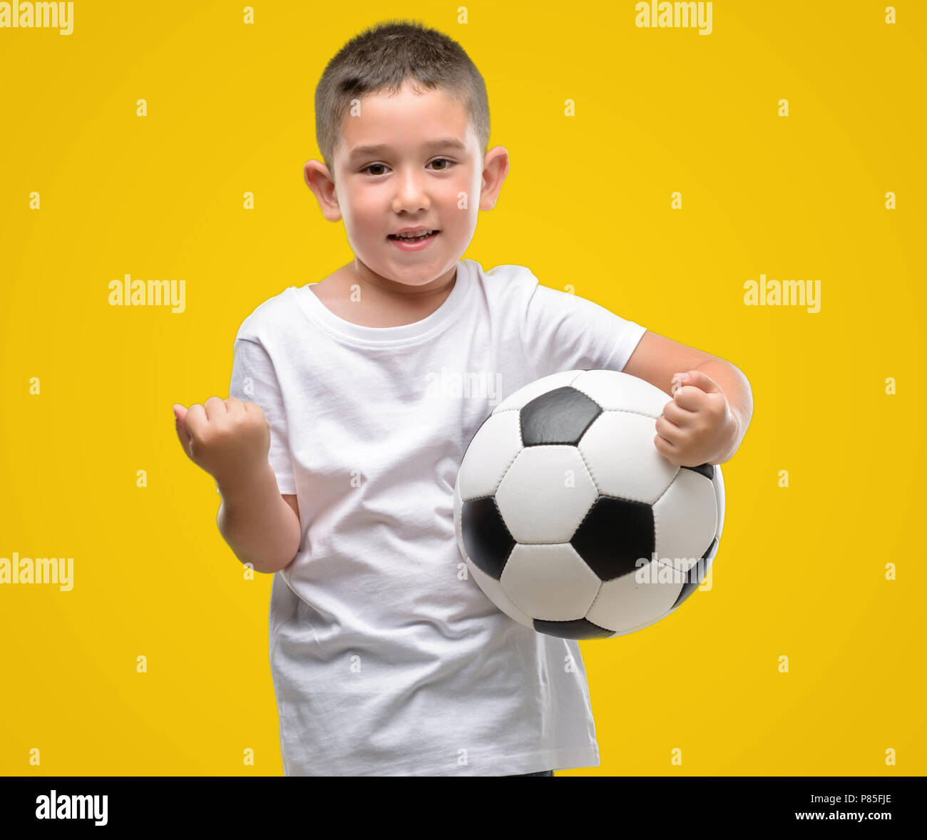 Dark haired little child playing with soccer ball screaming proud and ...