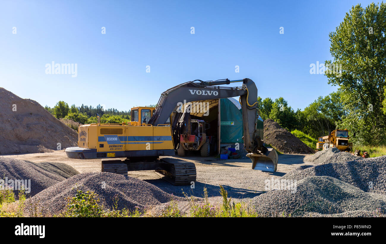 Articulated excavator in the middle of big piles of construction ...