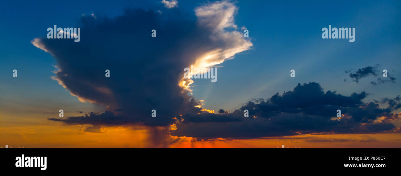 Beautiful sky at sunset with a huge cloud in dark orange and dark blue ...