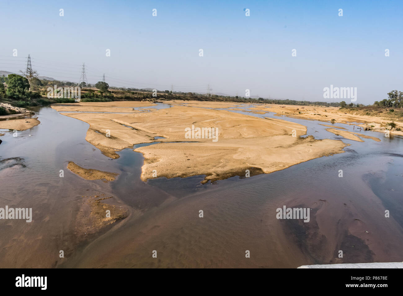Indian river with clean water in sandy bed with power grid cable laying ...