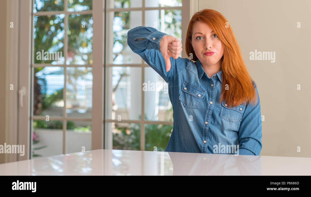 Redhead woman at home with angry face, negative sign showing dislike ...