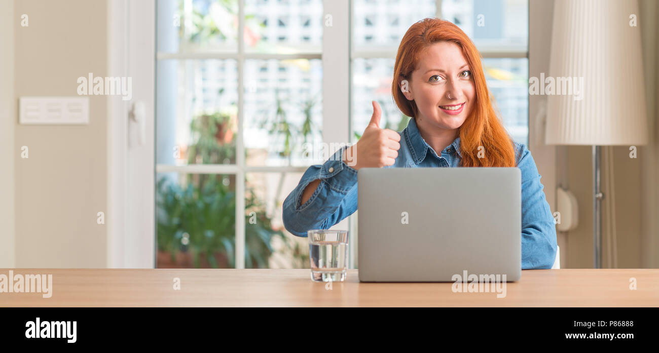 Redhead woman using computer laptop at home happy with big smile doing ...