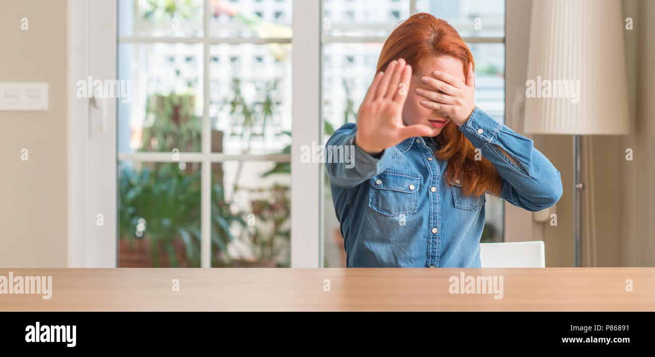 Redhead woman at home covering eyes with hands and doing stop gesture ...