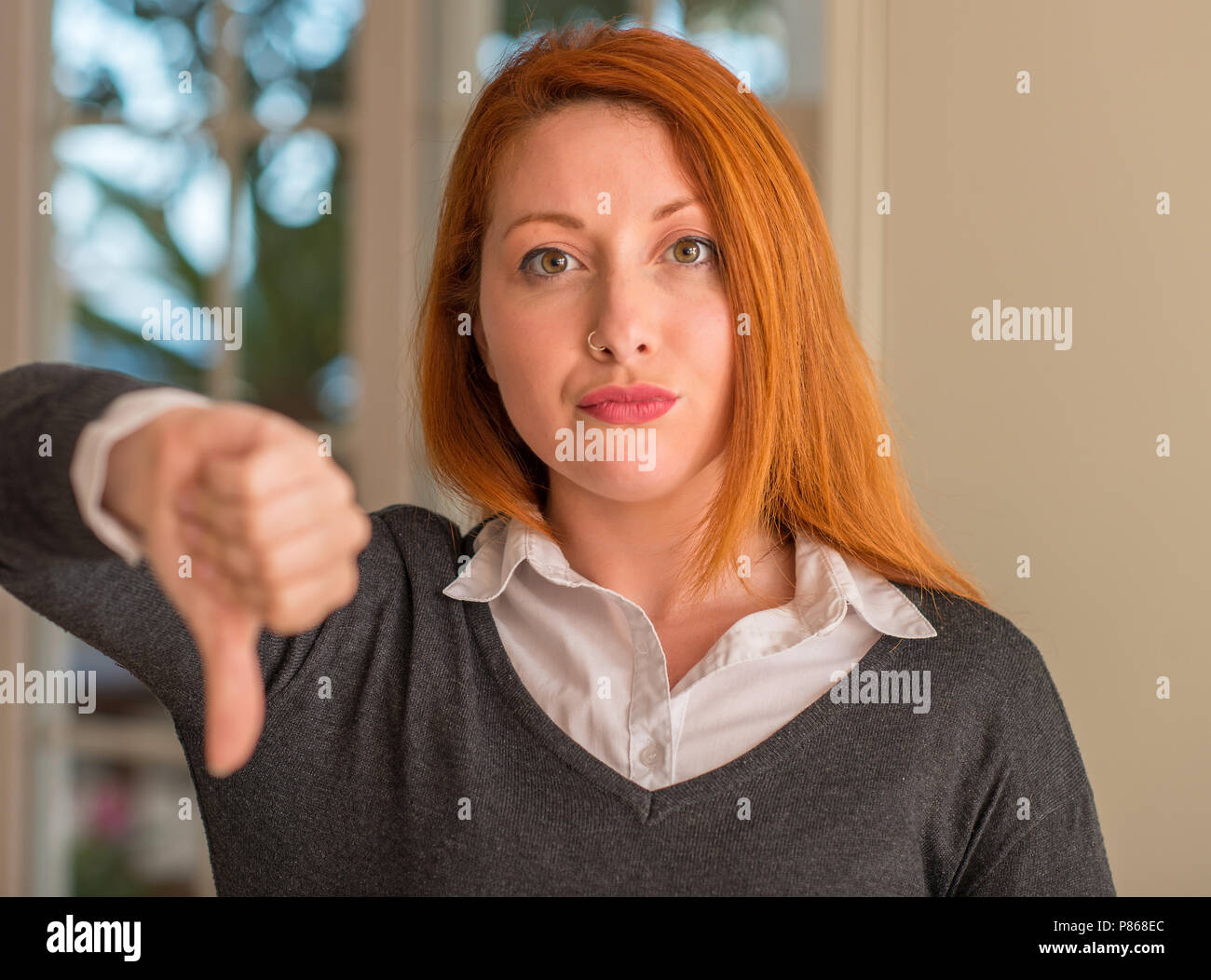Redhead woman at home with angry face, negative sign showing dislike ...