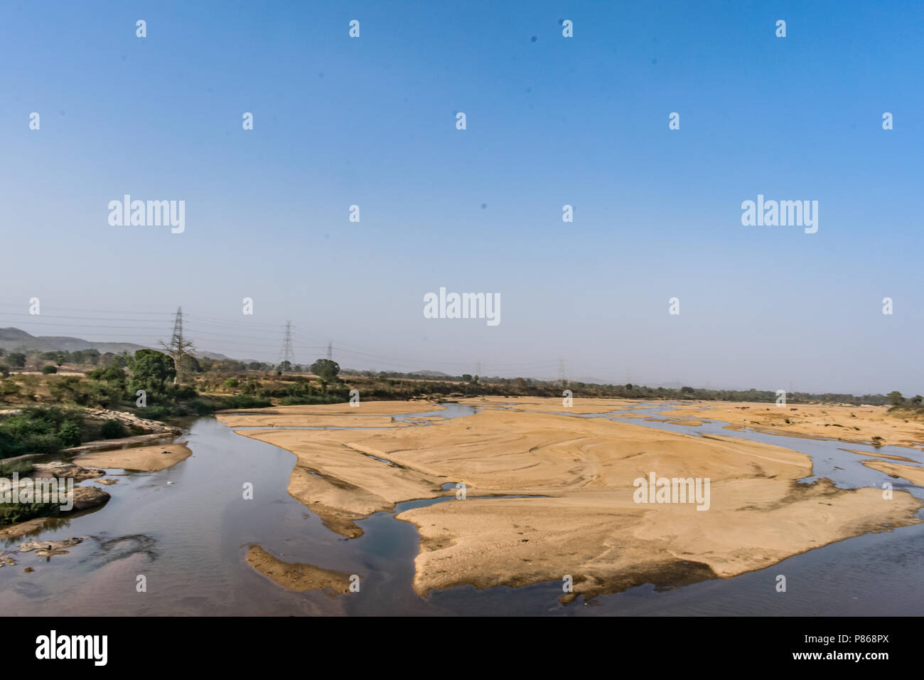 Indian river with clean water in sandy bed with power grid cable laying ...
