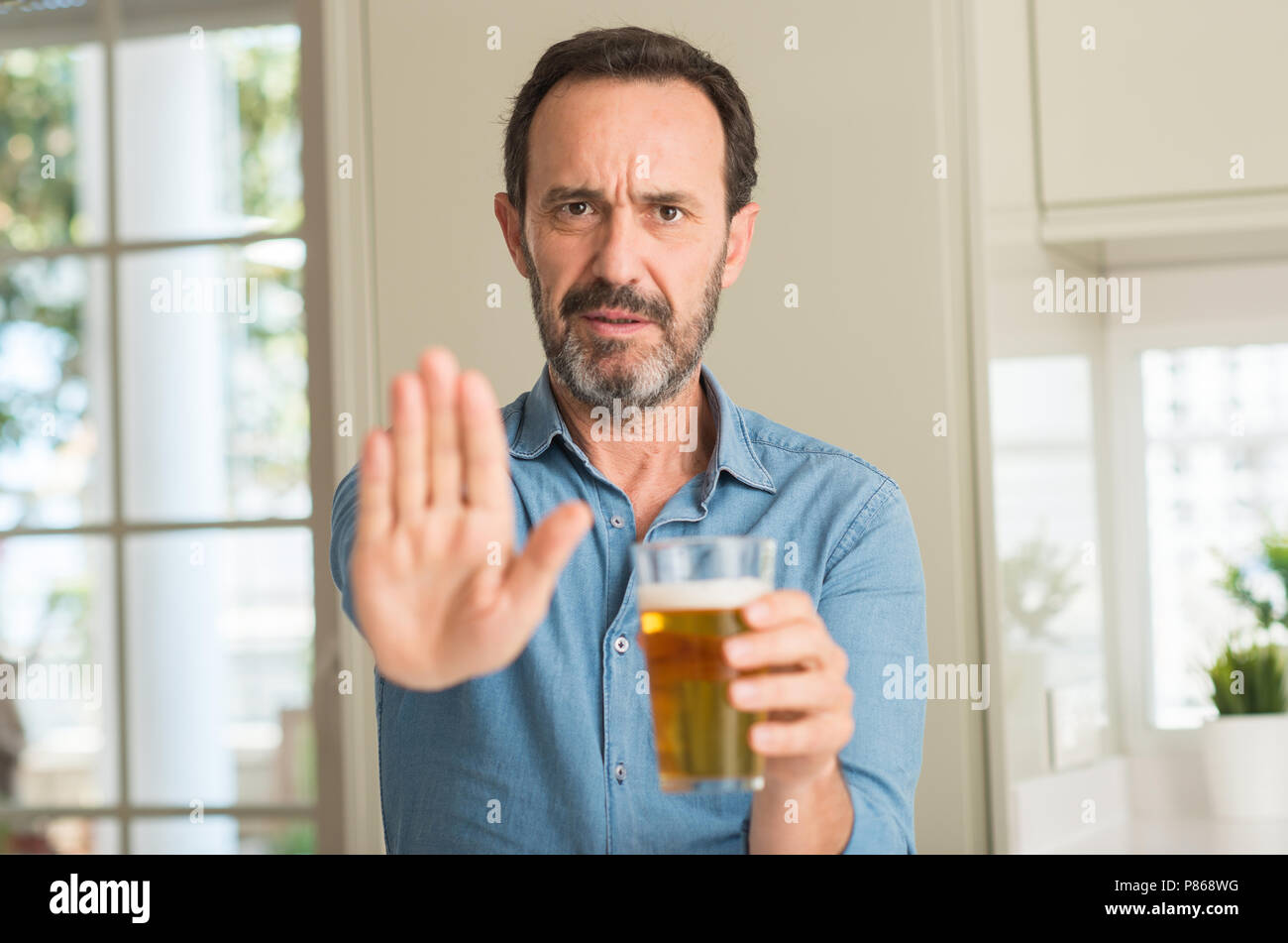Middle age man drinking beer with open hand doing stop sign with ...