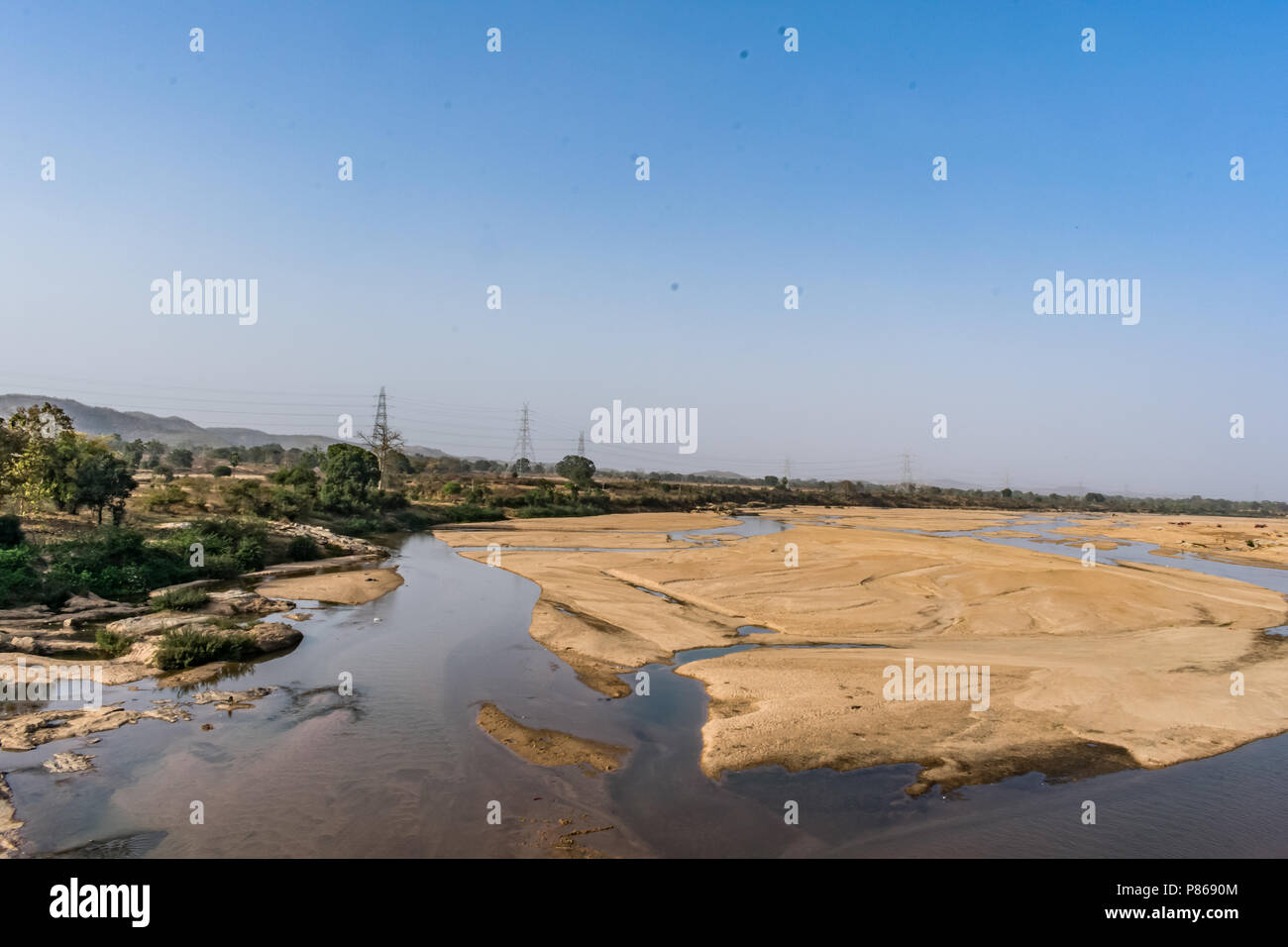 Indian river with clean water in sandy bed with power grid cable laying ...