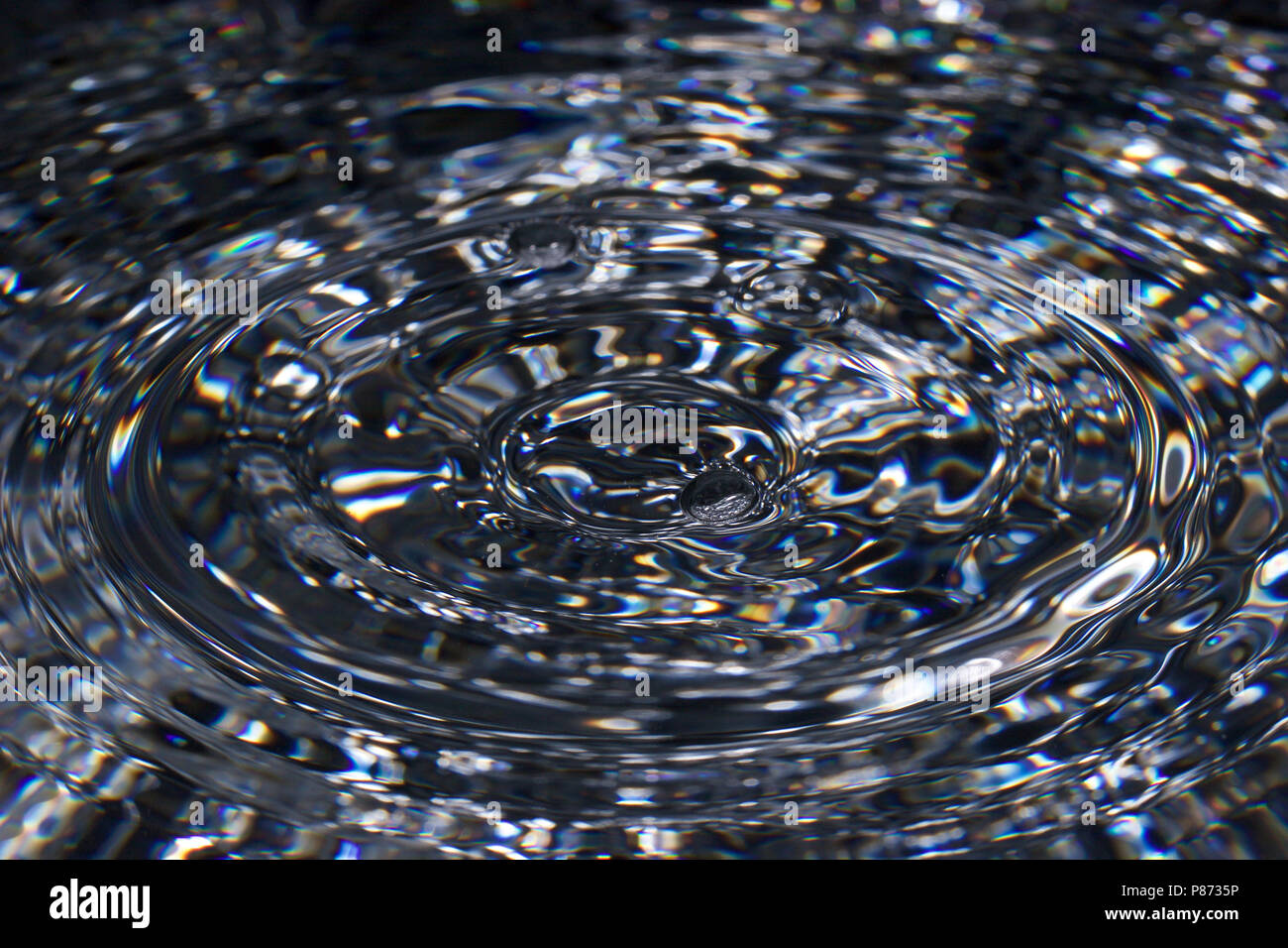 Water droplets falling into water causing splashes and ripples Stock ...