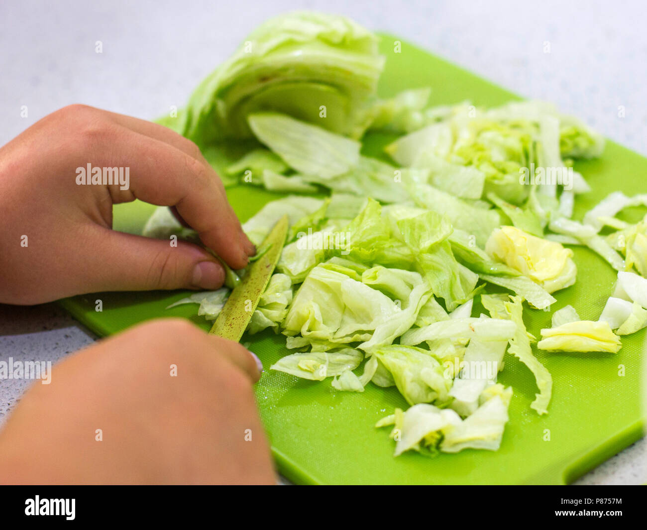 Hands cut a lettuce salad with a knife on green board Stock Photo - Alamy
