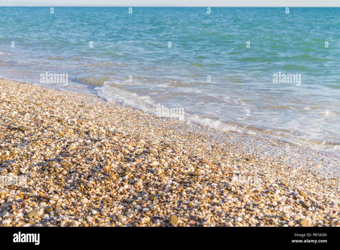 A wave of the sea running on a sandy and pebble beach Stock Photo - Alamy