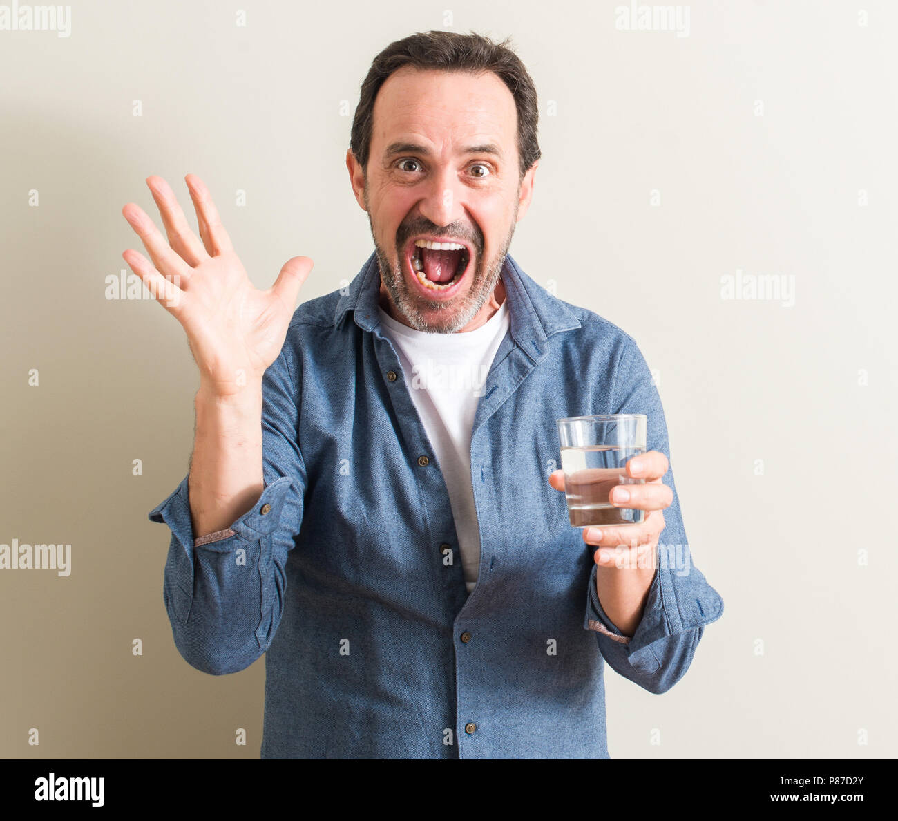 Senior man drinking water in a glass very happy and excited, winner ...