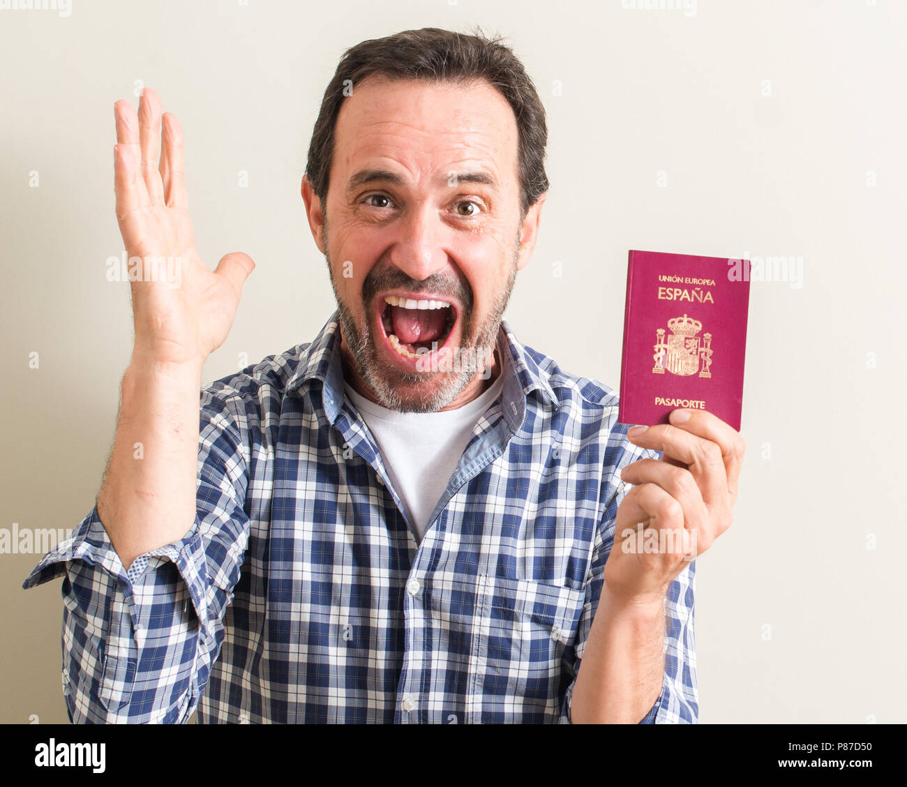 Senior man holding spanish passport very happy and excited, winner ...