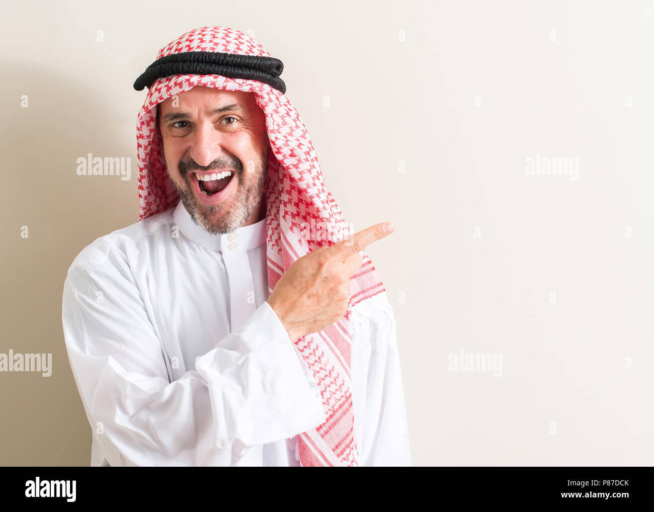 Senior arabic man very happy pointing with hand and finger to the side ...