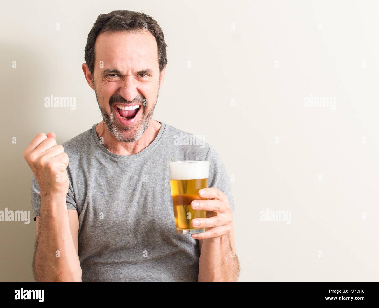 Senior man drinking beer screaming proud and celebrating victory and ...