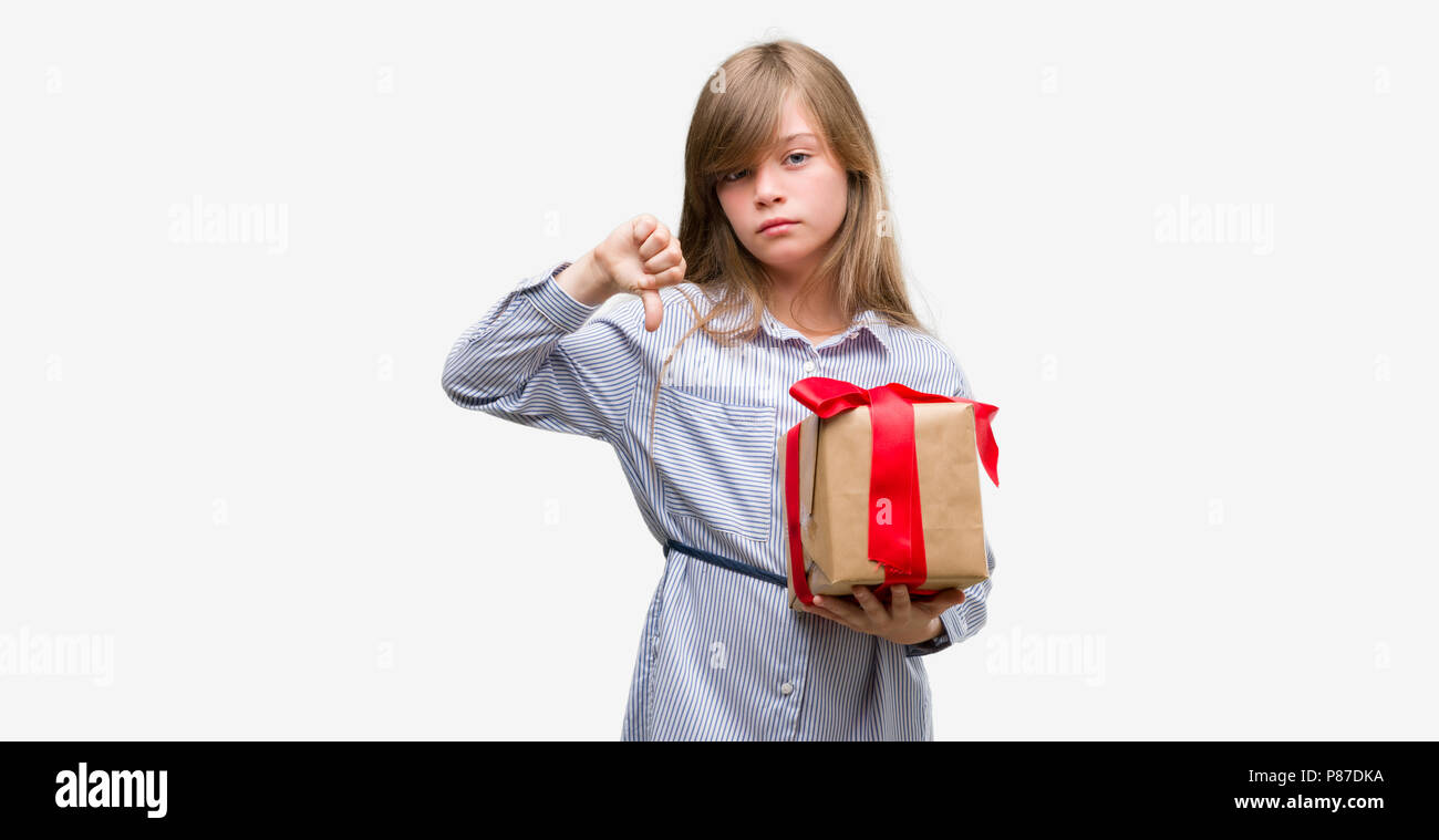 Young blonde toddler holding a present with angry face, negative sign ...