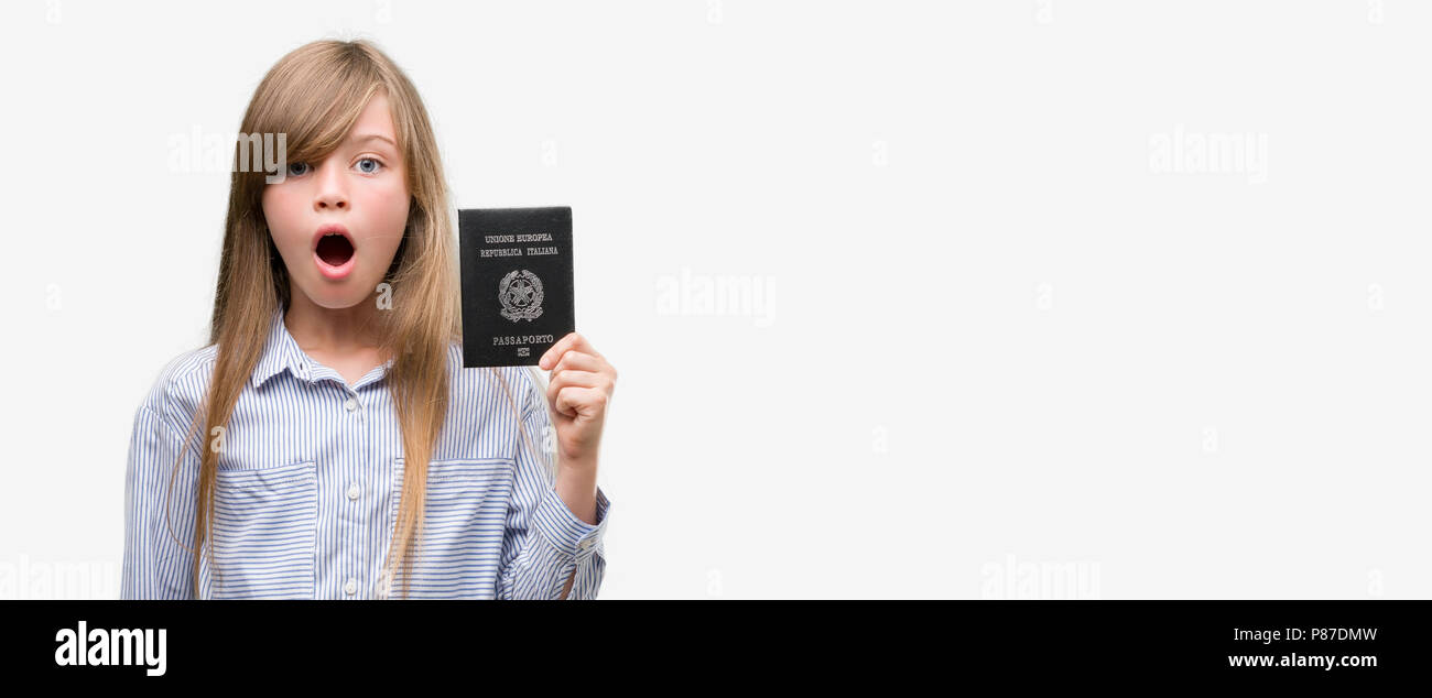 Young blonde toddler holding italian passport scared in shock with a ...