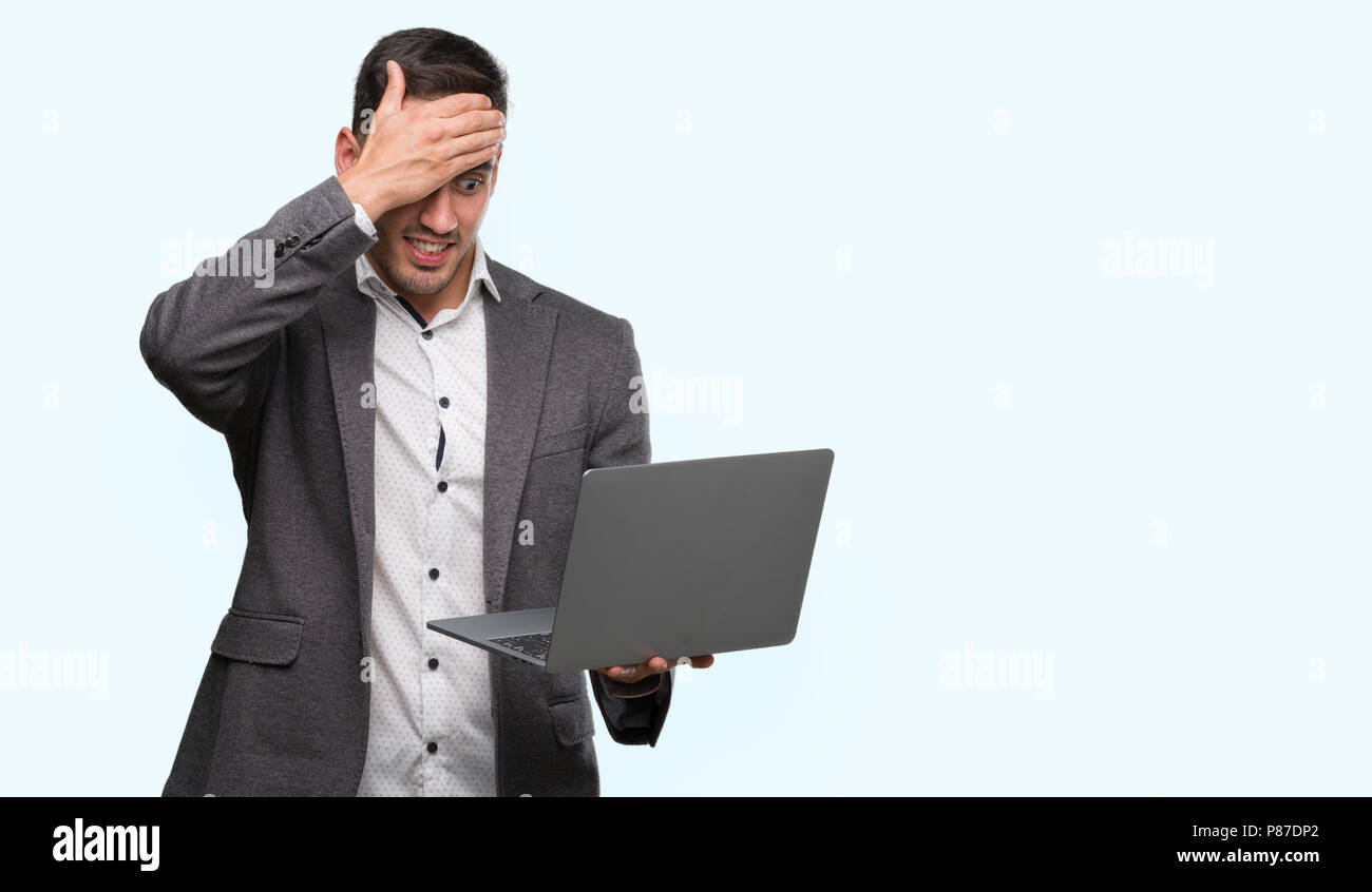 Handsome young man using computer laptop stressed with hand on head ...