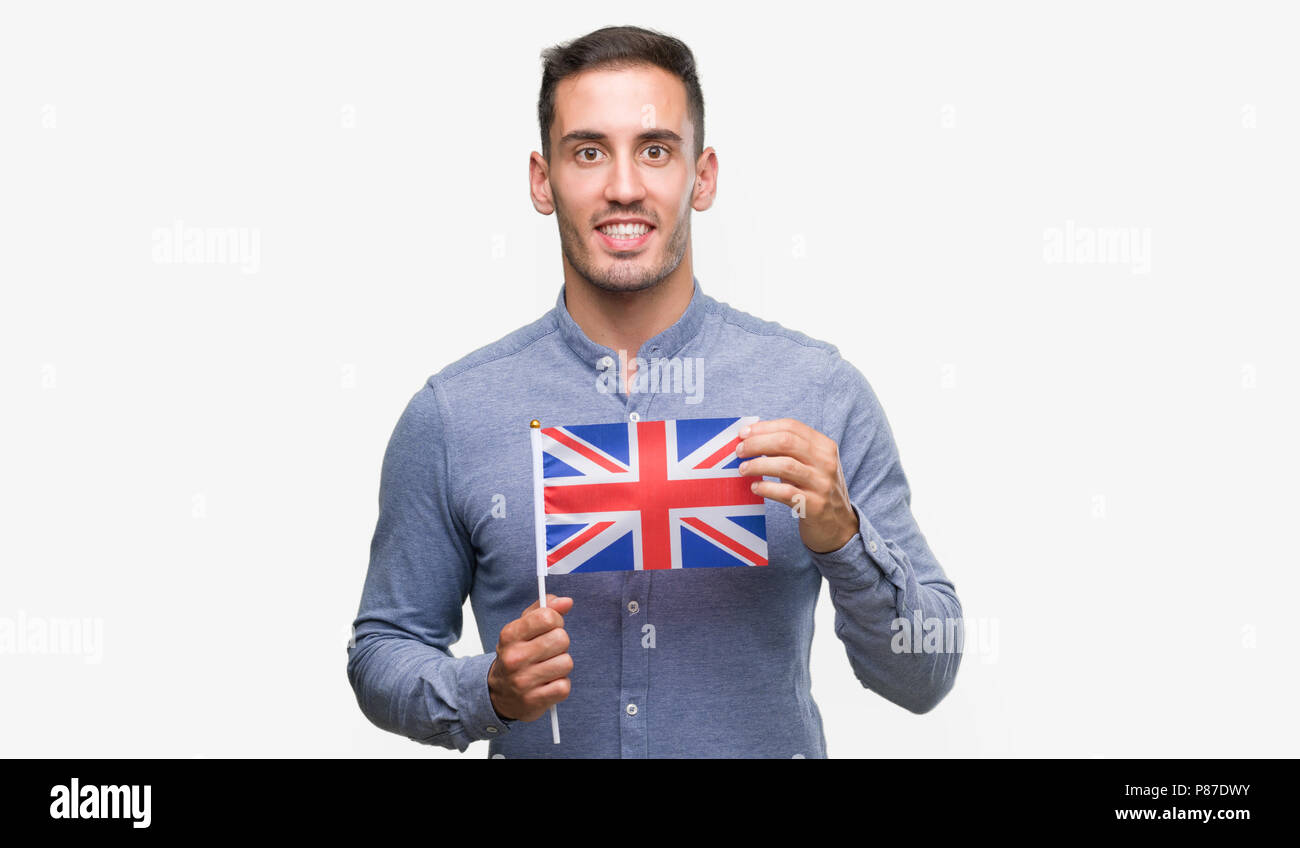 Handsome young man holding a flag of United Kingdom with a happy face ...