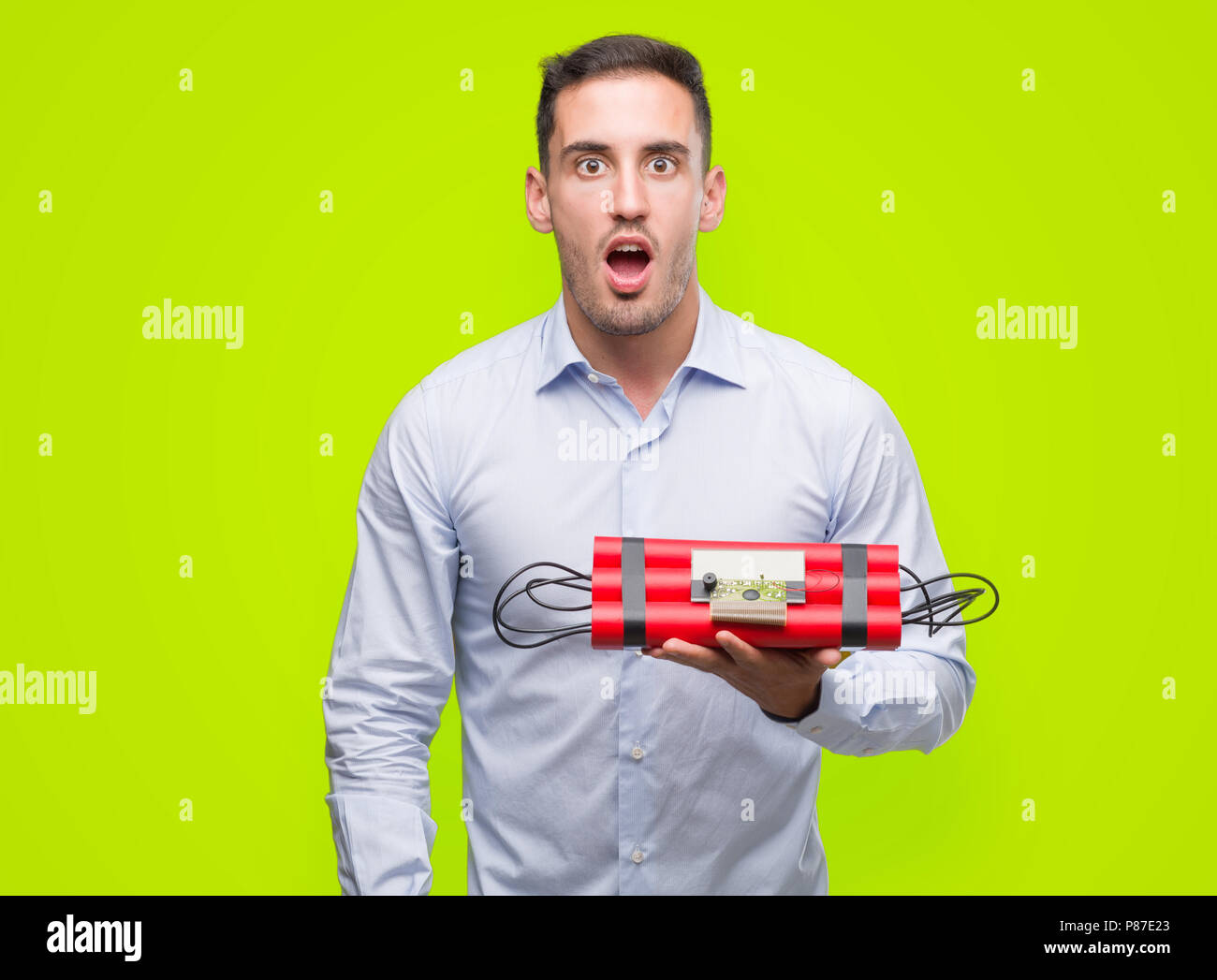 Handsome young business man holding an alarm clock bomb scared in shock ...