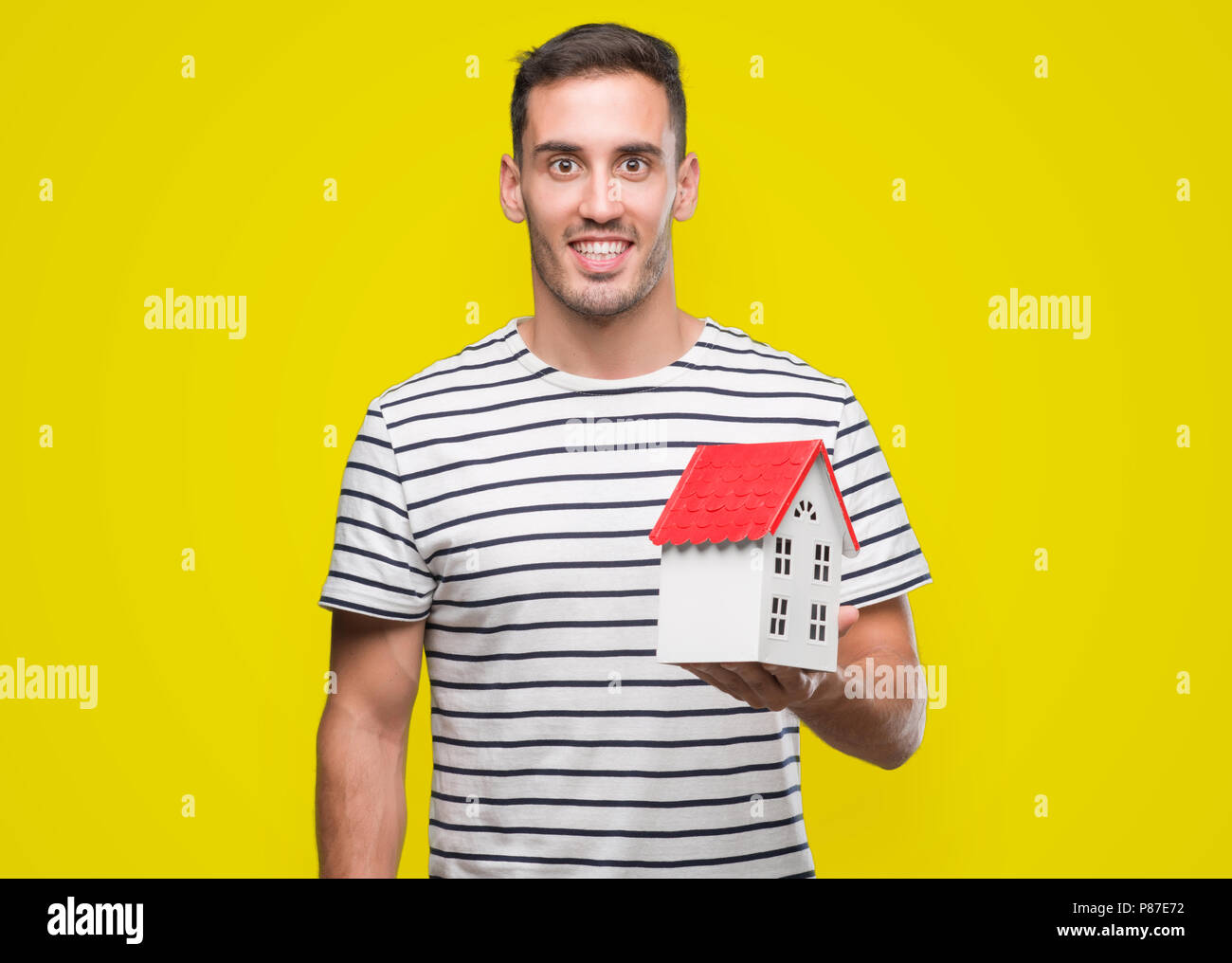 Handsome real estate agent holding a house with a happy face standing ...